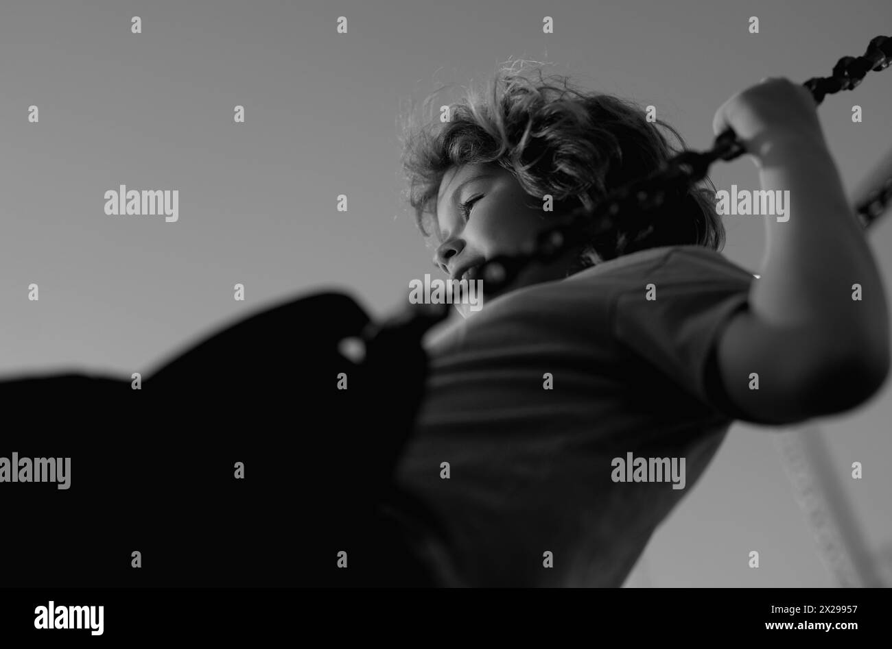 Child swinging on chain swing on city kids playground. Swing ride. Cute child having fun on a ...