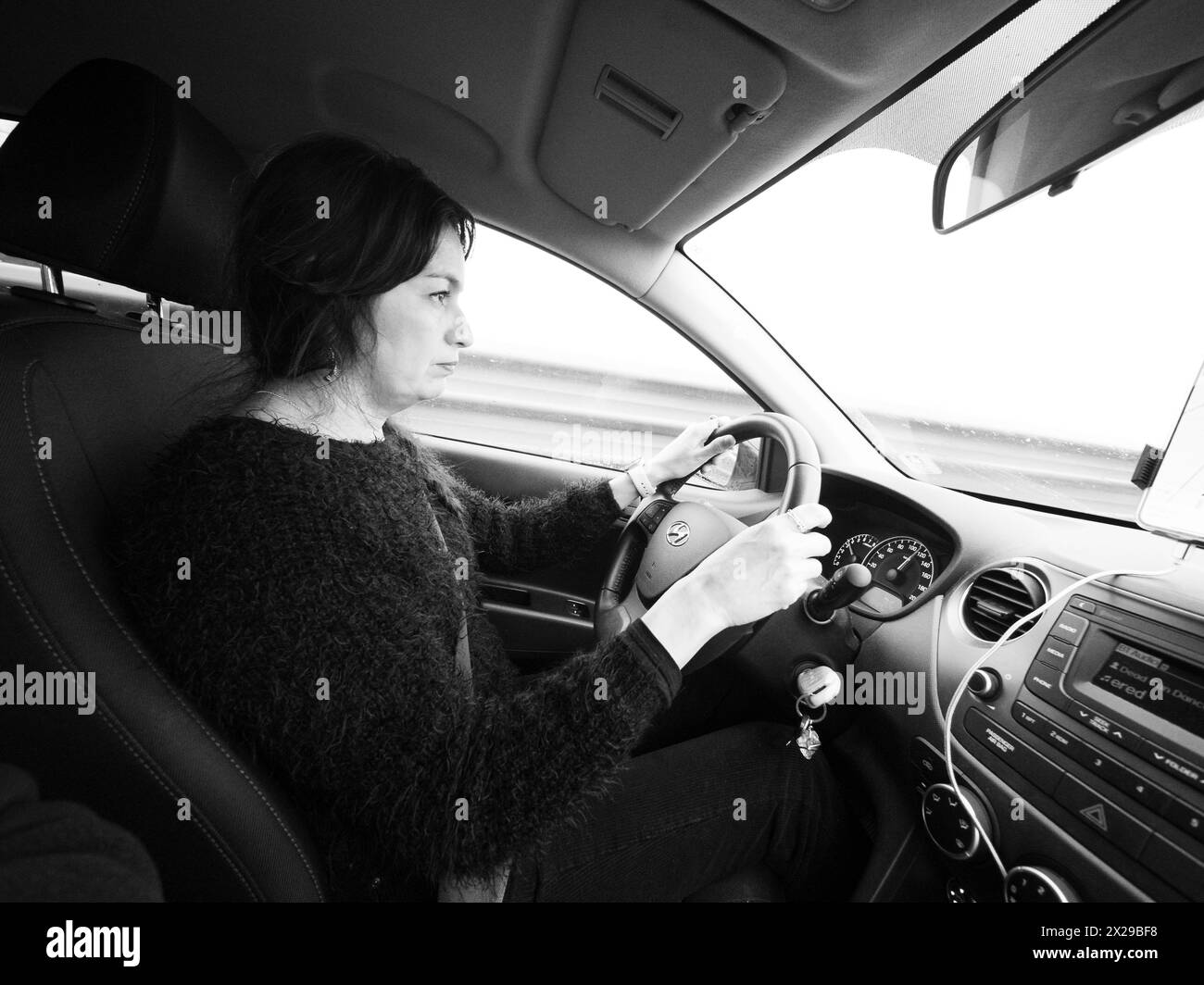 A woman is driving a car with a steering wheel and a dashboard Stock ...