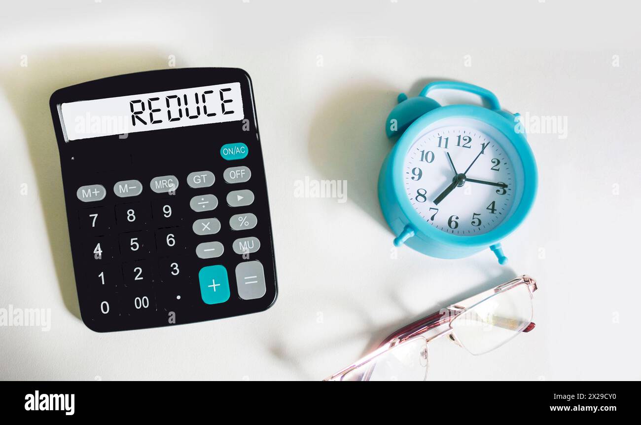 Reduce word written on calculator and white background with clock and ...