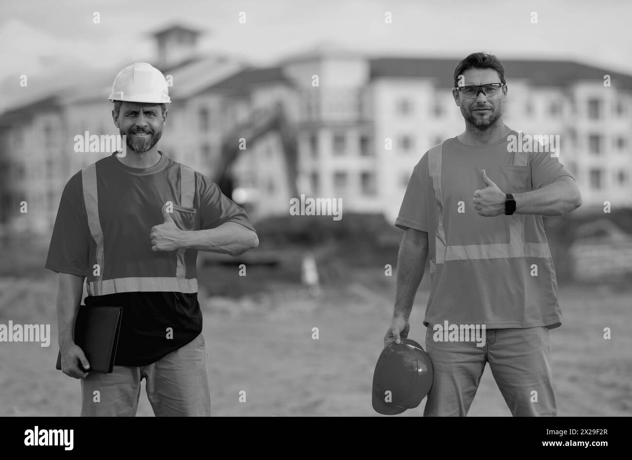 Two construction workers with hardhat helmet on construction site ...