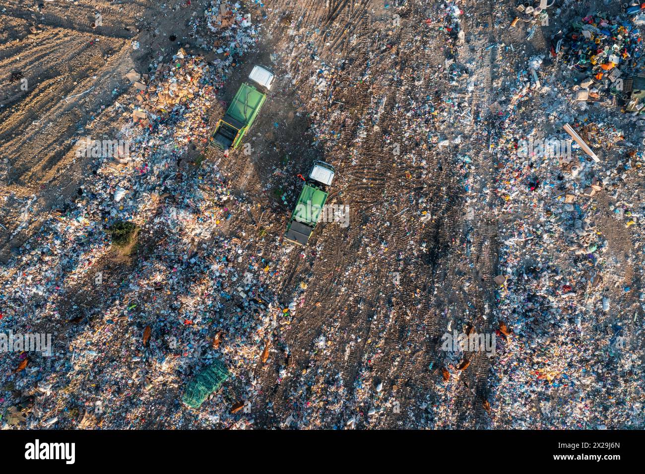 Aerial top down view of garbage trucks unload pile of waste at landfill ...