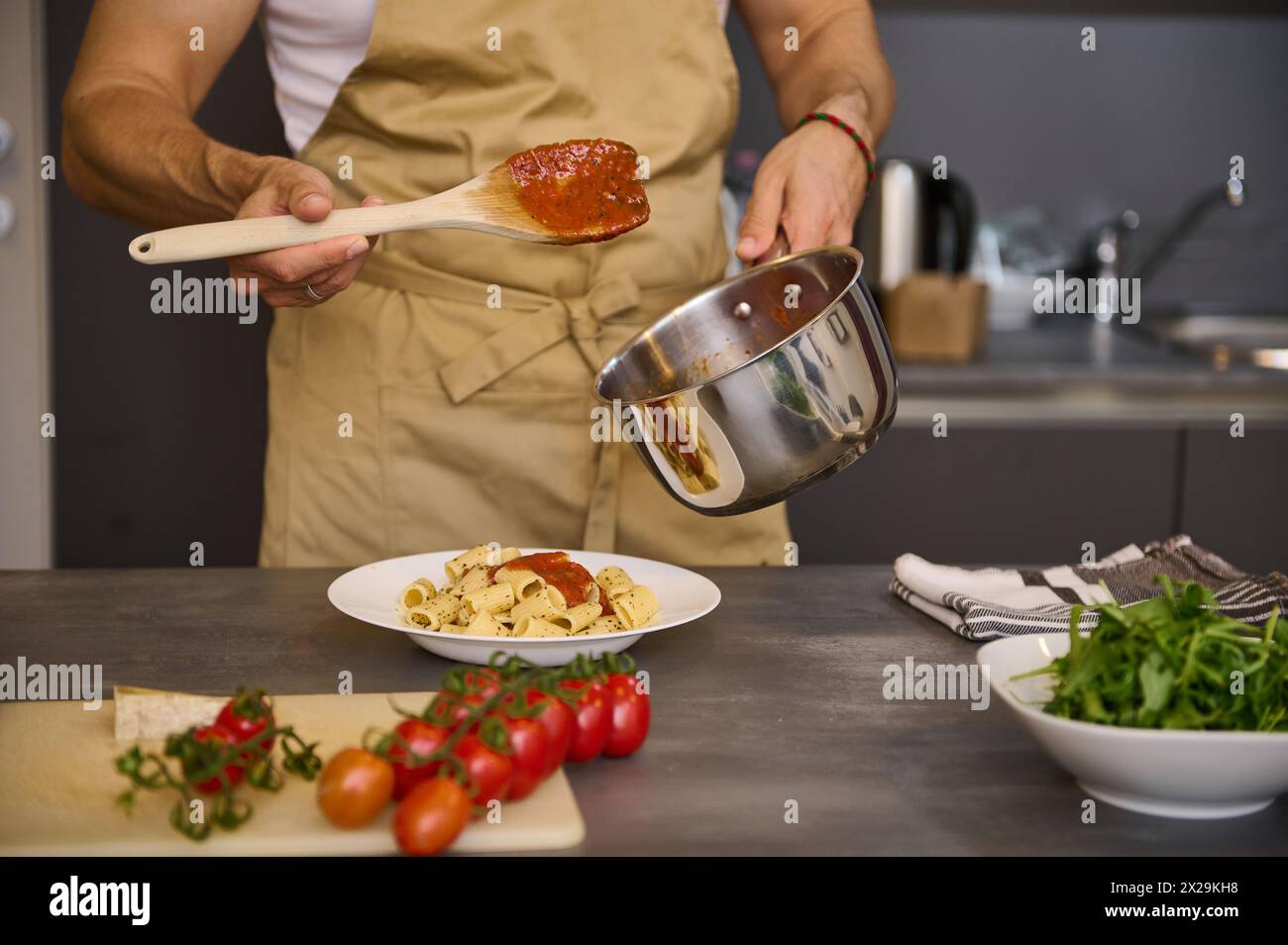 Close-up chef pouring tomato sauce on Italian pasta, plating up the ...