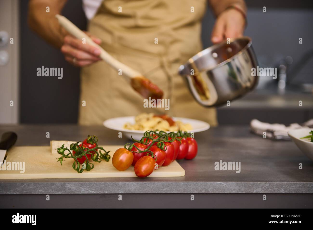 Focus on a branch of fresh ripe organic tomato cherry on the cutting board against the backdrop ...