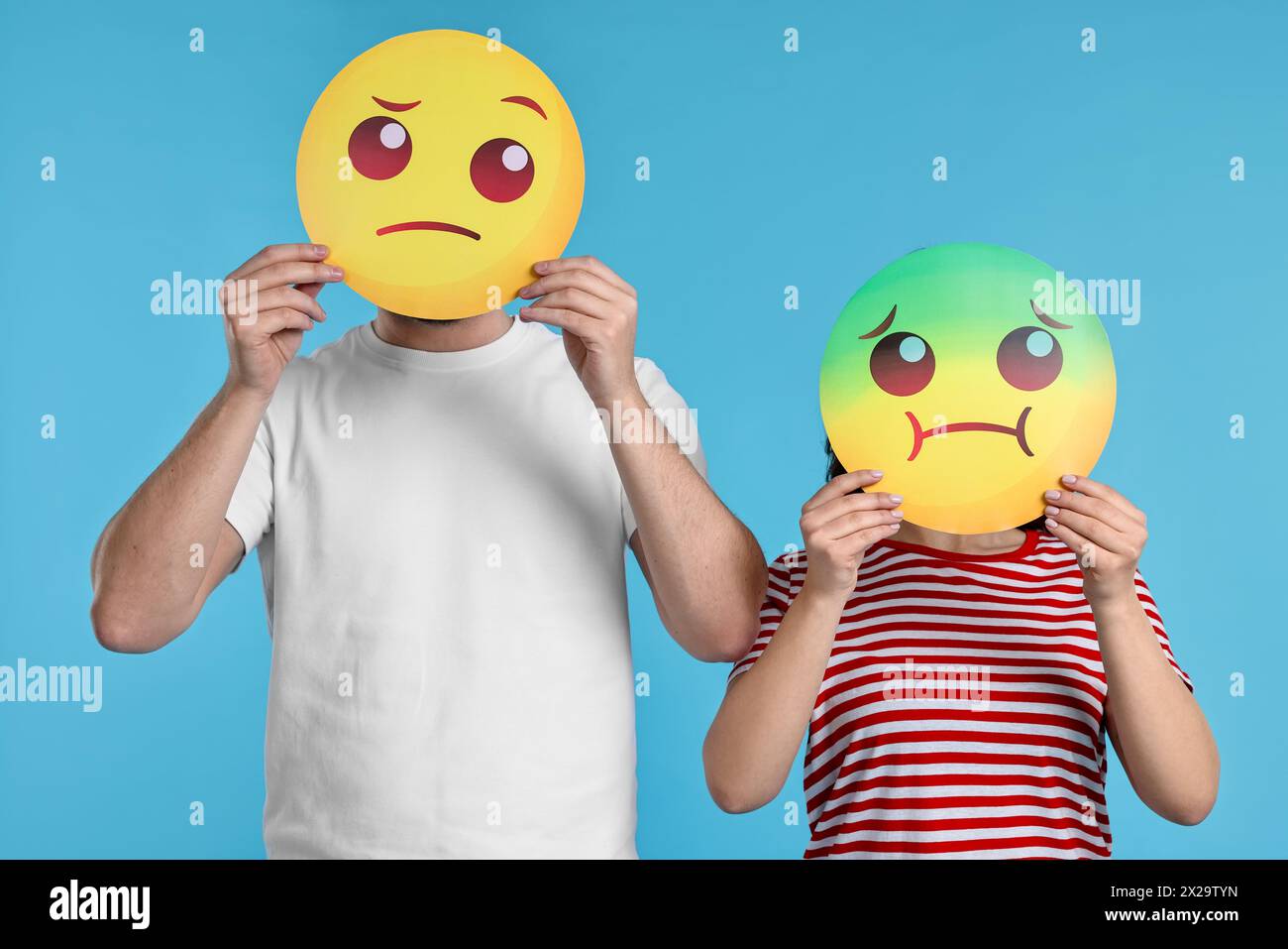 People covering faces with emoticons on light blue background Stock ...