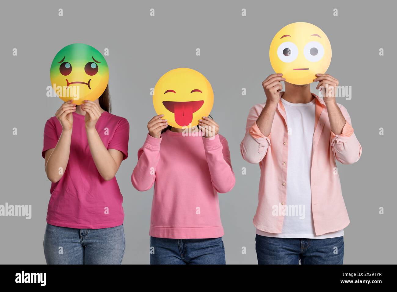 People covering faces with emoticons on grey background Stock Photo - Alamy