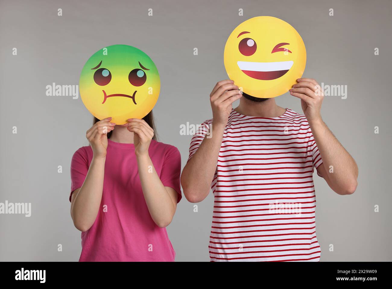 People covering faces with emoticons on grey background Stock Photo - Alamy