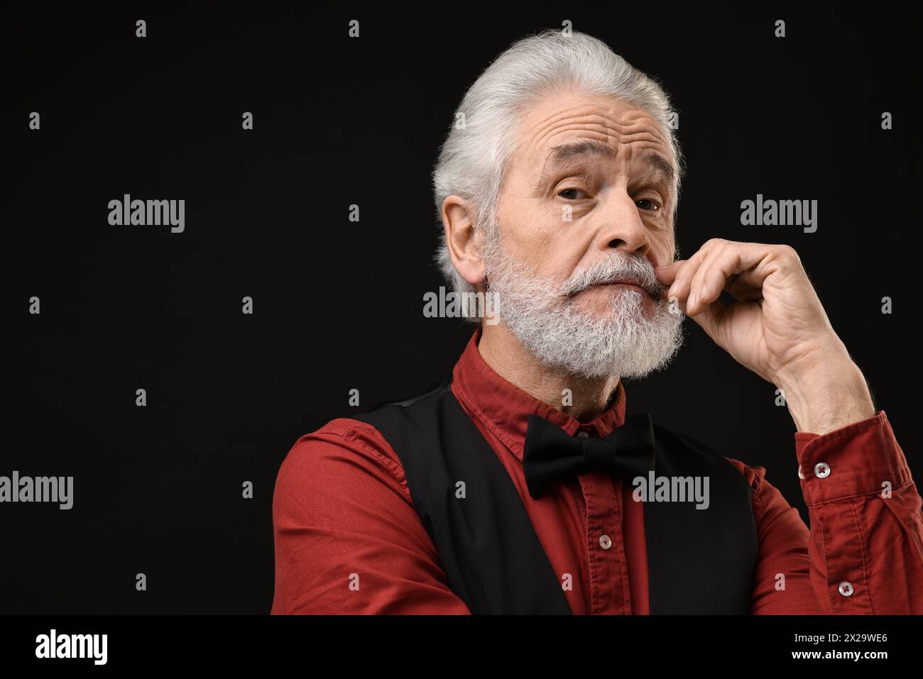 Senior man touching mustache on black background, space for text Stock ...
