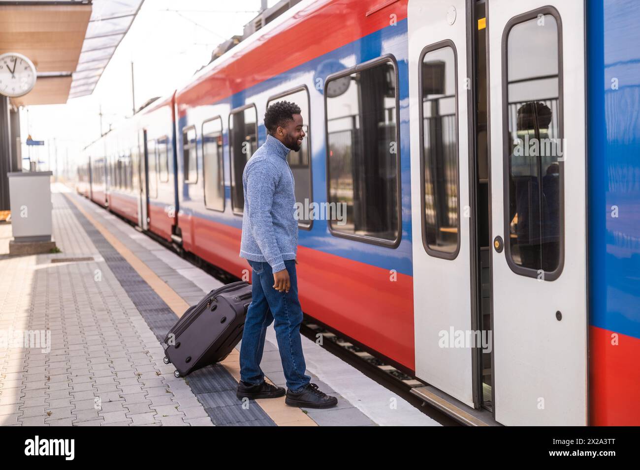 Happy man with suitcase entering into the train on station Stock Photo ...
