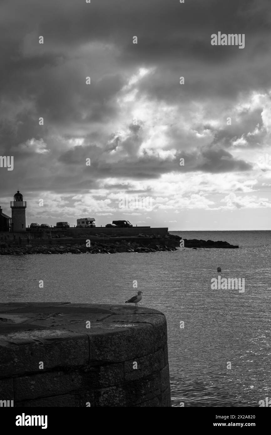 Black and white of old lighthouse and harbour at portpatrick beach ...