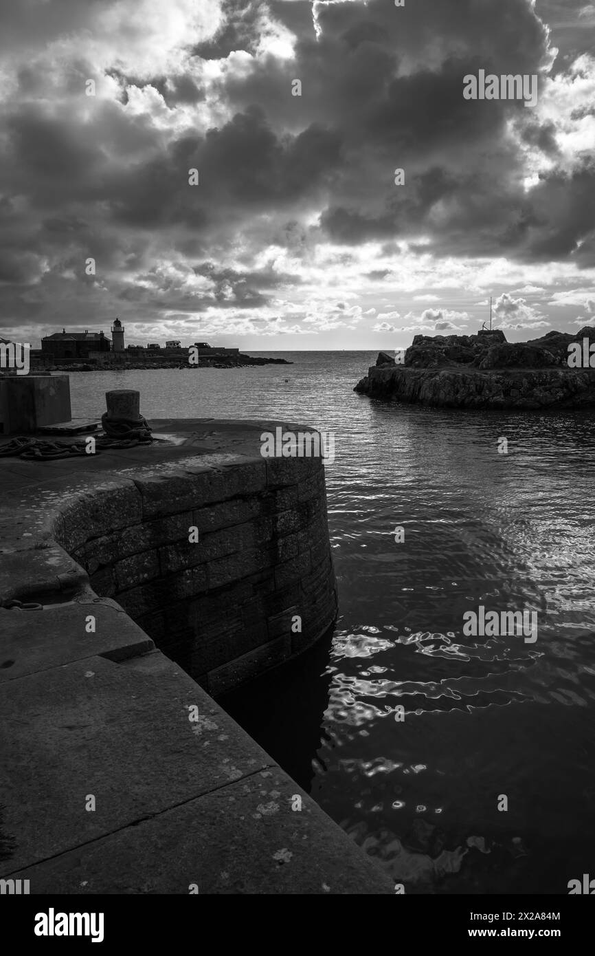 Black and white of old lighthouse and harbour at portpatrick beach ...
