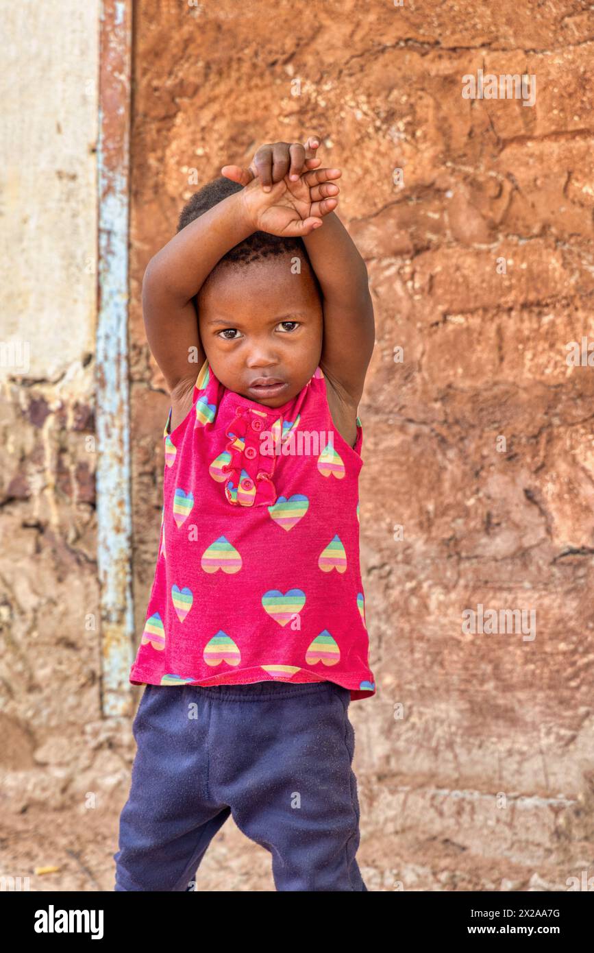 single african villager child playing outdoors in front of the house in ...