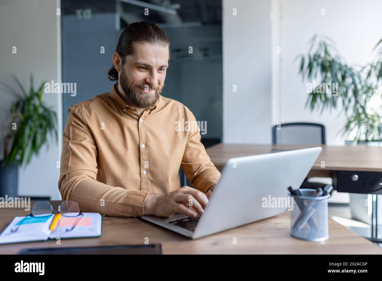 Positive office environment as a professional man with a beard smiles ...