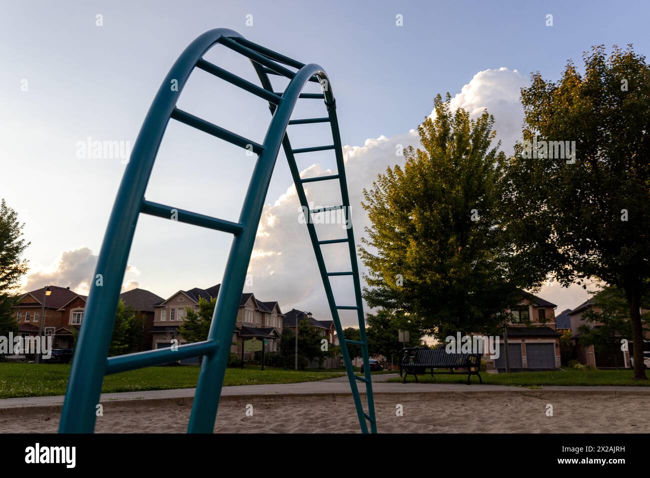 Blue playground ladder - suburban homes, green tree, cloudy sky in ...