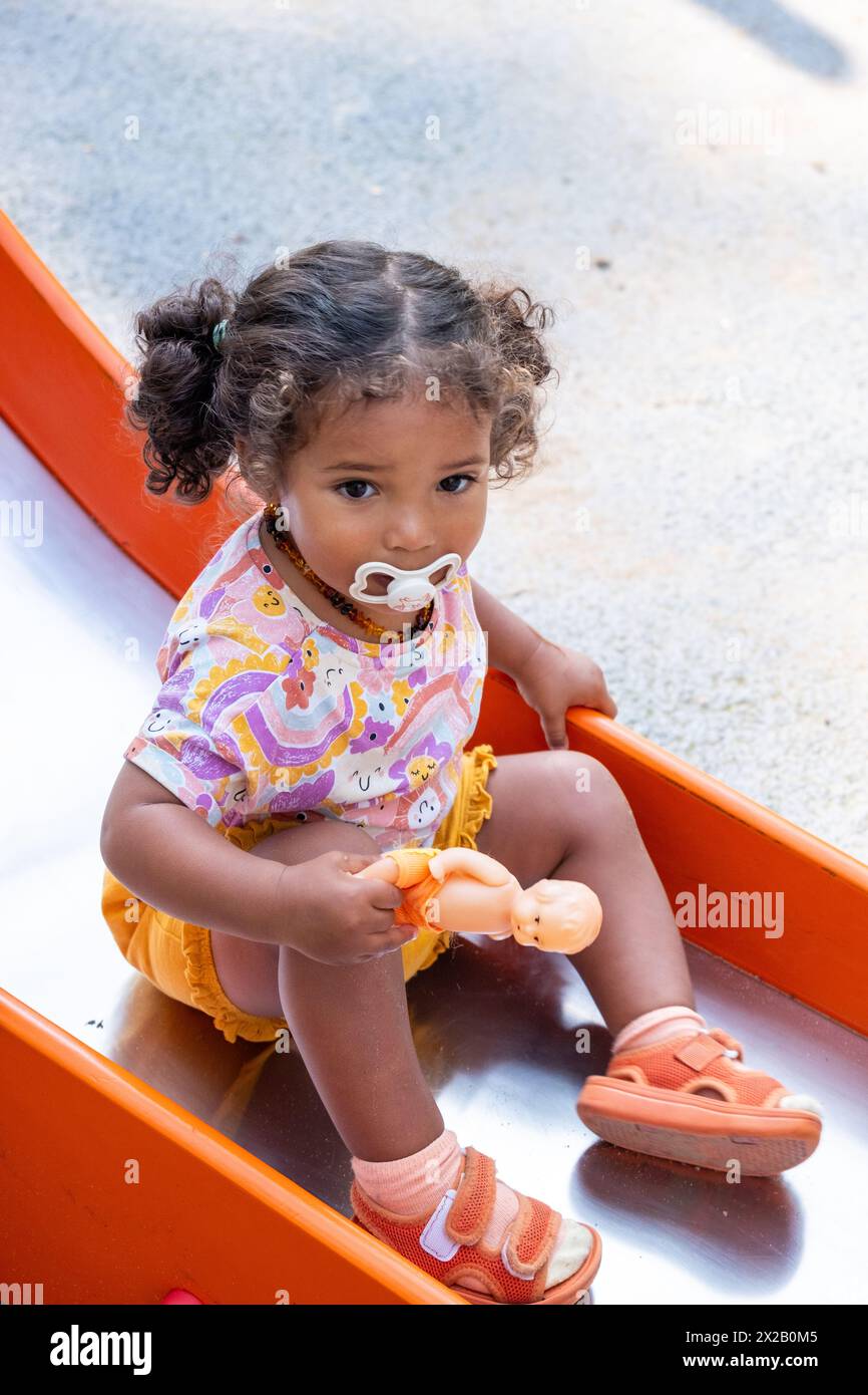 African American Toddler with a pacifier on a slide, the innocence of ...