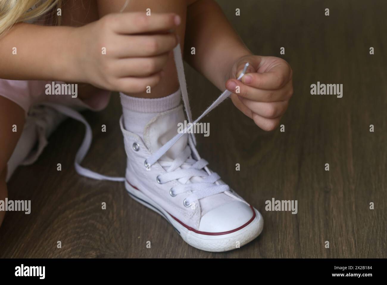 Kid tying shoes. Little girl struggling to tie shoe laces. Child learning fine motor skills ...