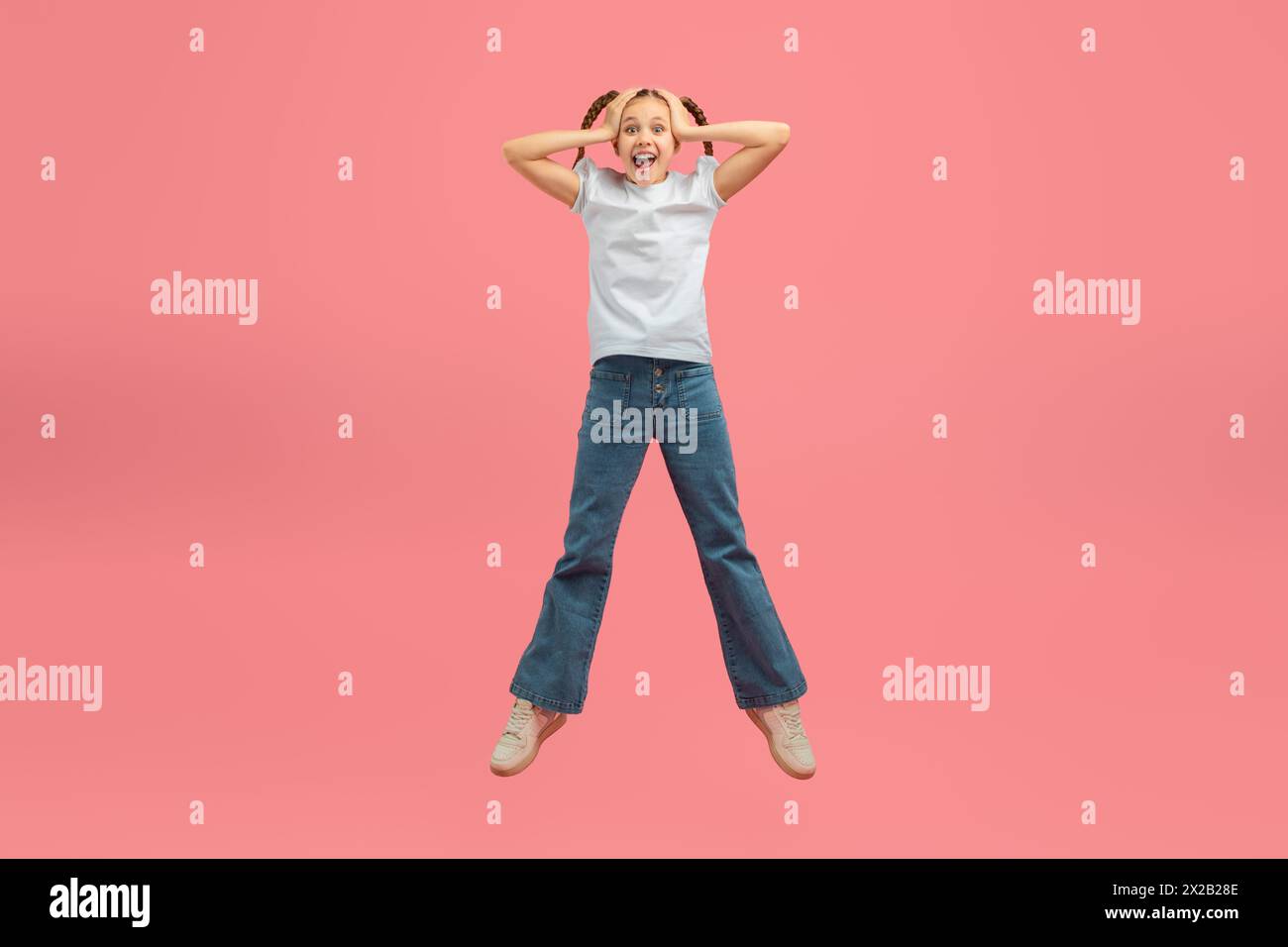 Excited teen girl jumping with hands on head Stock Photo - Alamy