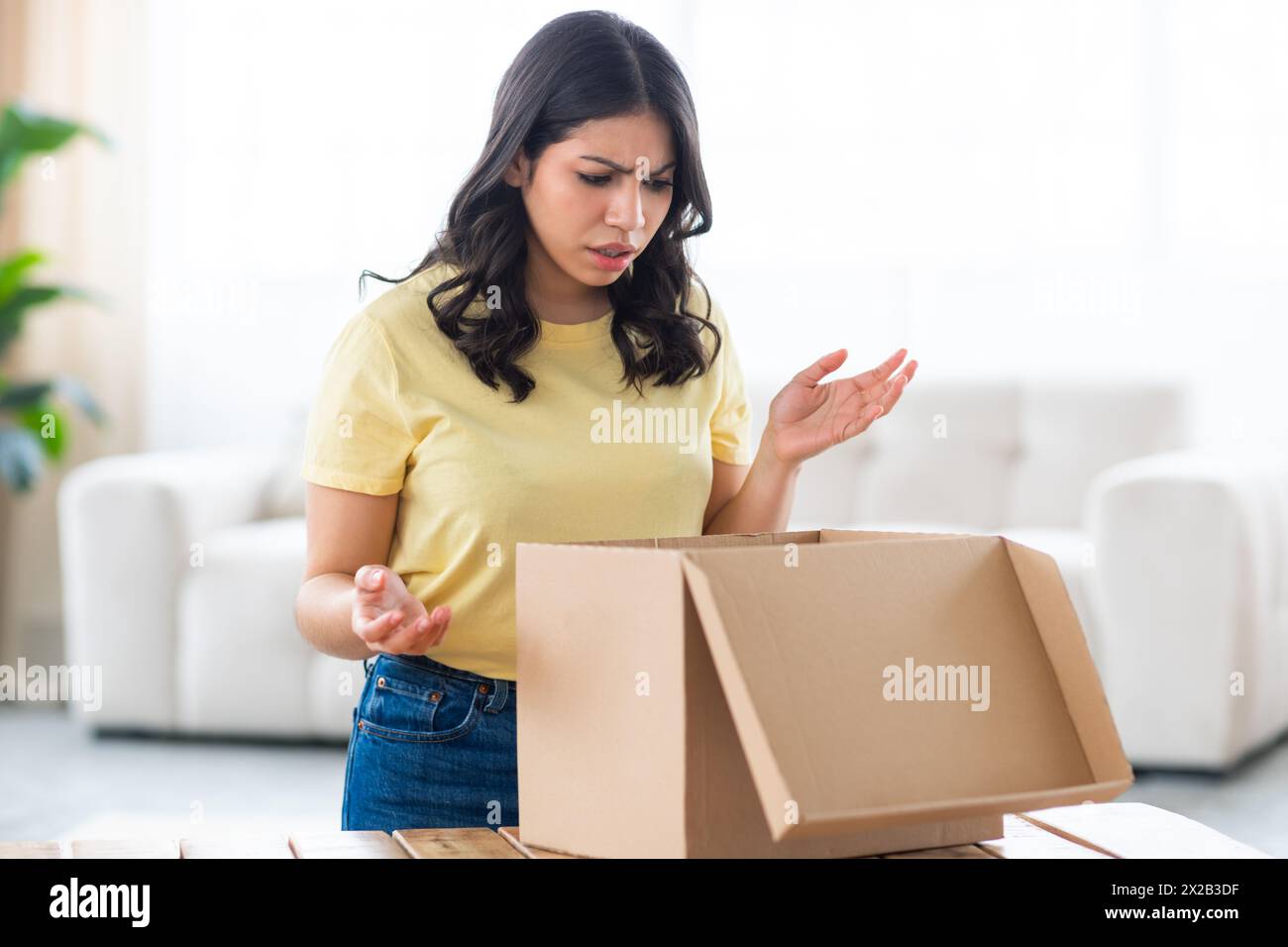 Woman disappointed by the content of a cardboard box Stock Photo - Alamy