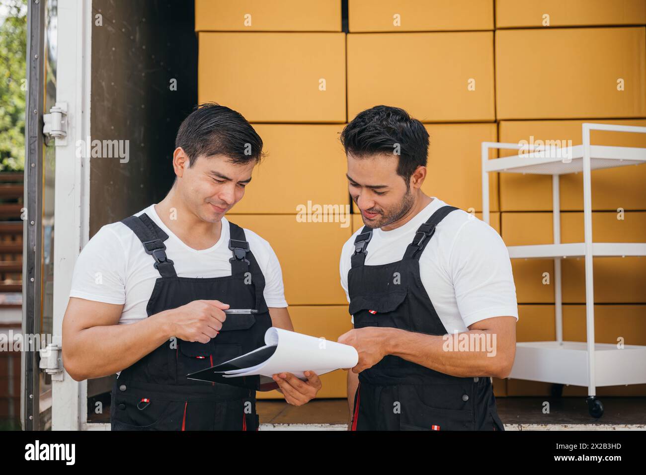 Employees outdoors unloading boxes and checking documents for the ...