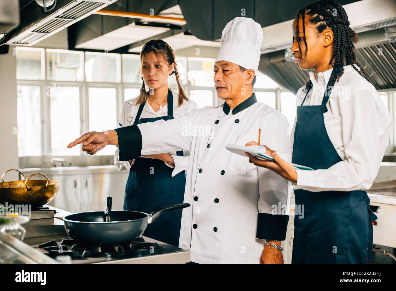 Asian senior chef in uniform educates multiracial students in a ...