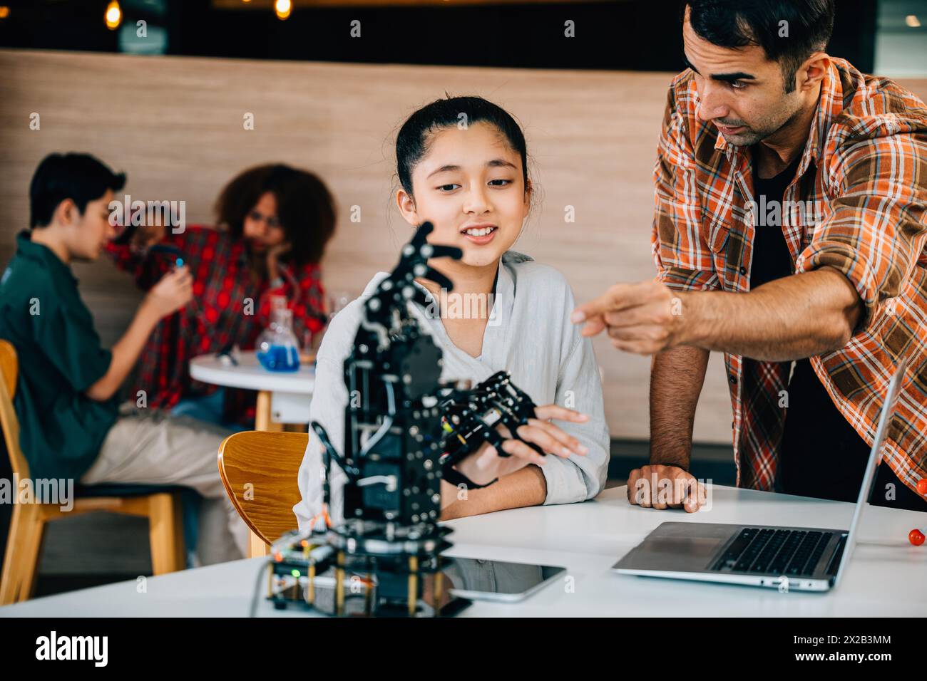 In classroom teacher aids student in building robotic arm for design ...