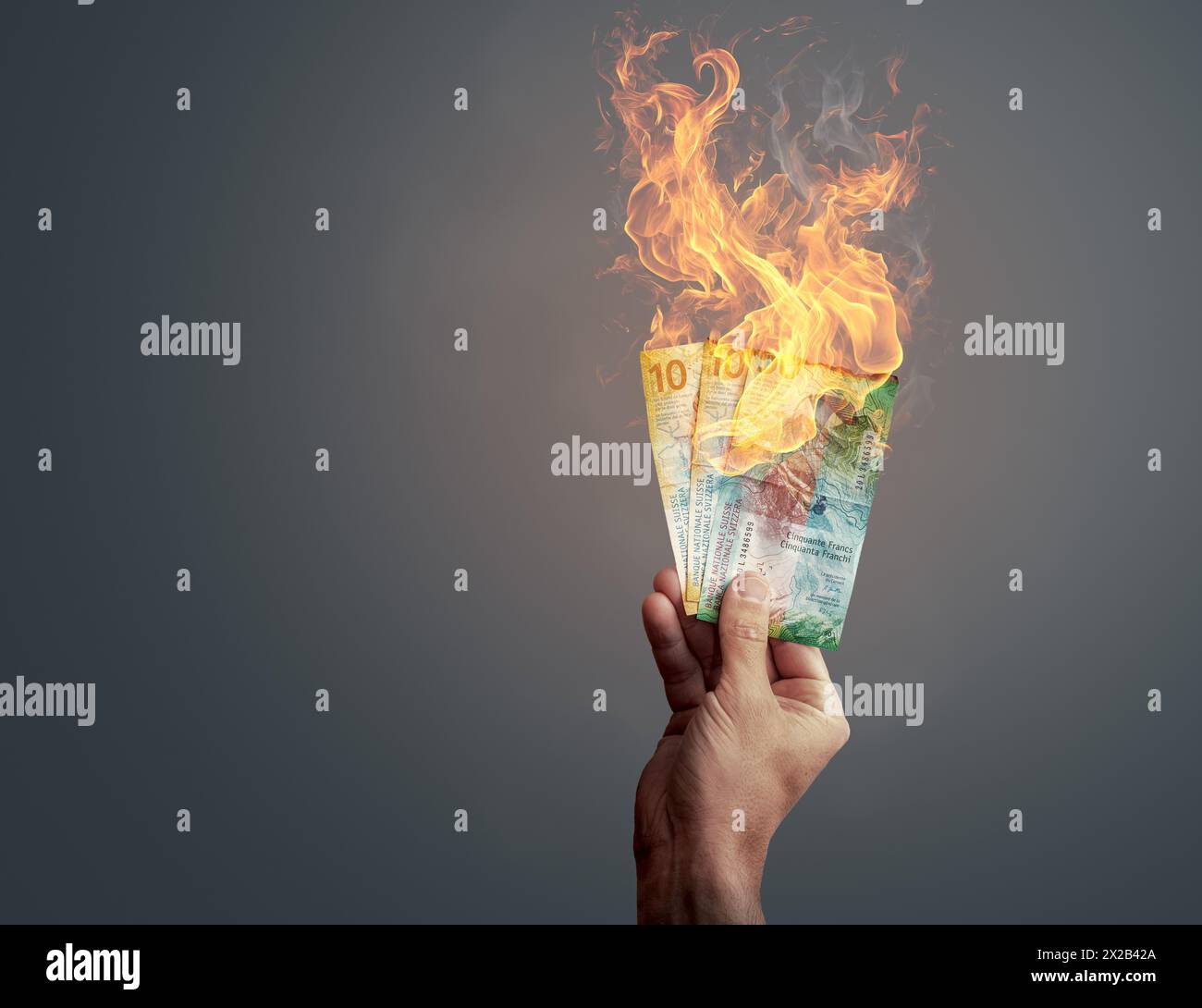 Hand holding burning Swiss franc banknotes showing concept of inflation ...