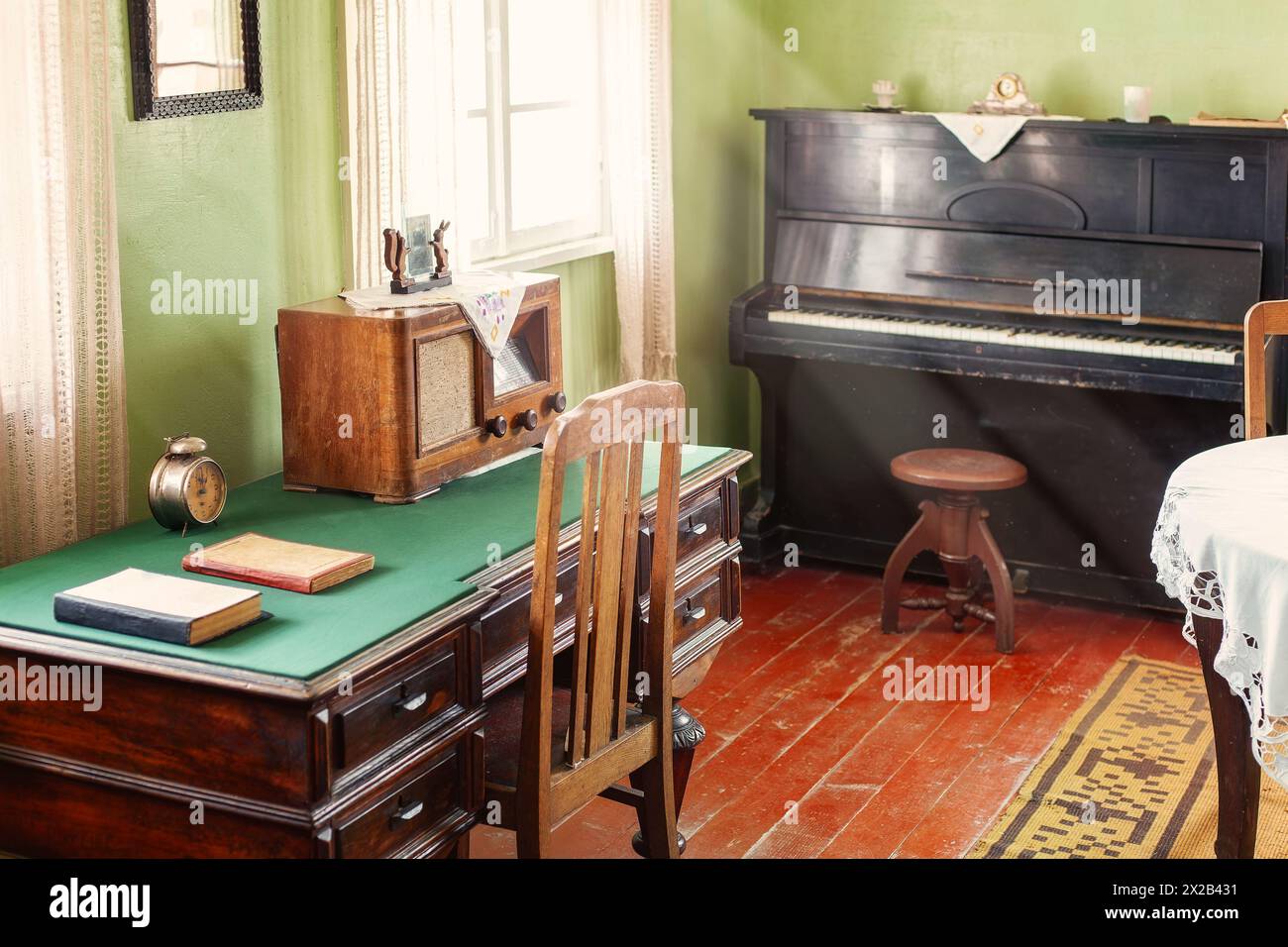 Antique study with desk, books, clock, radio and black piano. The ...