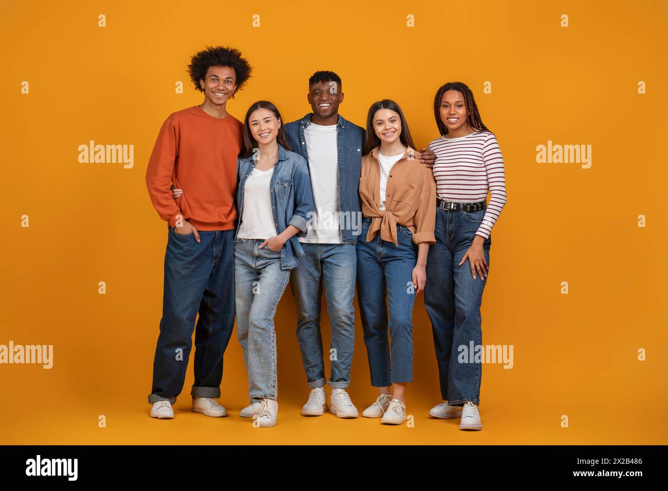 Happy multiethnic group standing together on orange background Stock ...