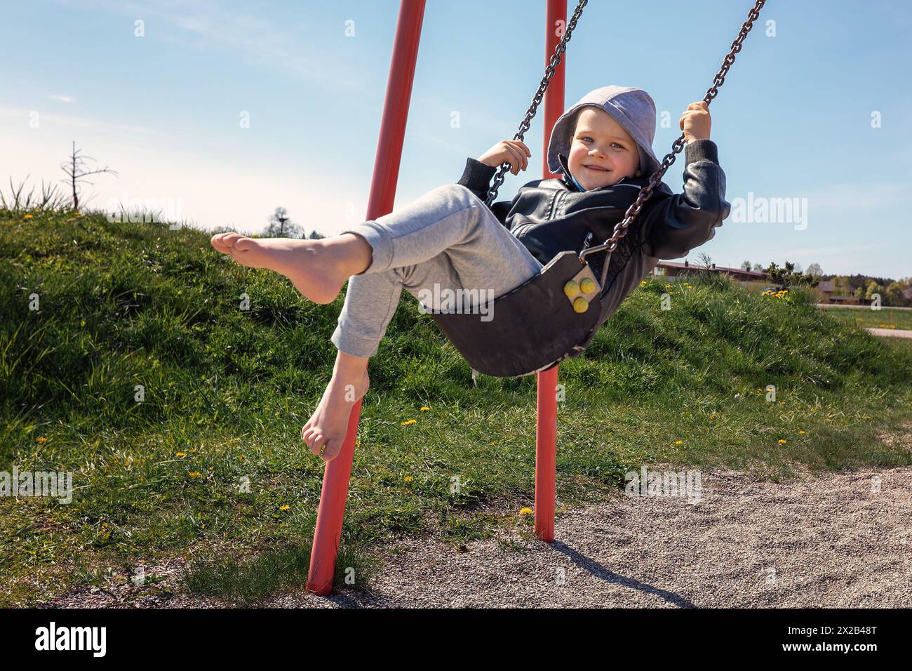 Smiling child on a swing in the field. A carefree childhood is a happy ...