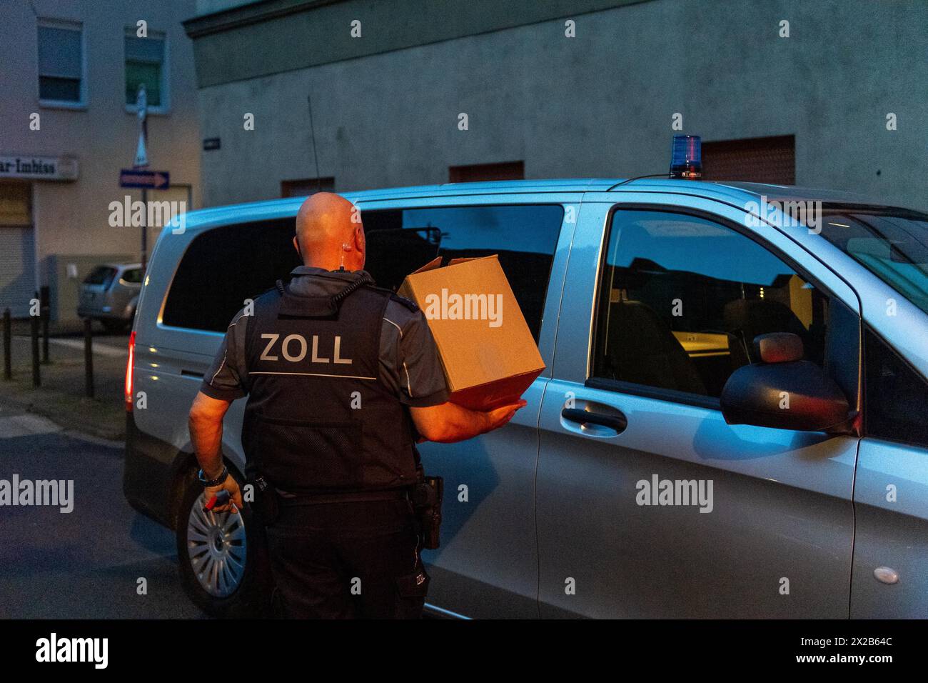 Customs officer at work, carrying cardboard to the official vehicle at ...