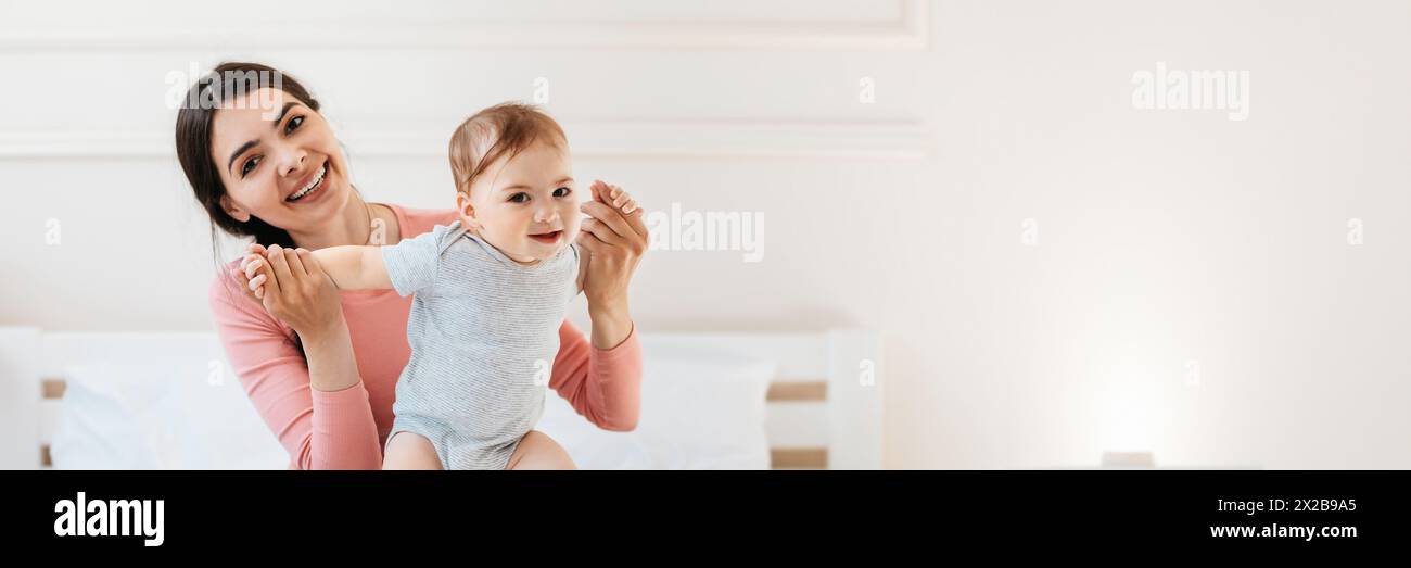Happy mom helping to her infant child making first steps Stock Photo ...