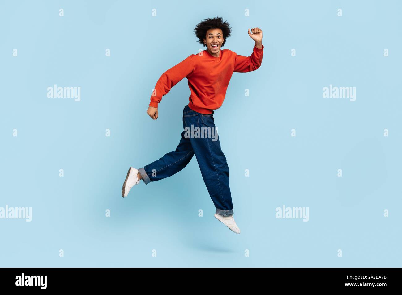 Exuberant young man running and smiling on blue background Stock Photo ...