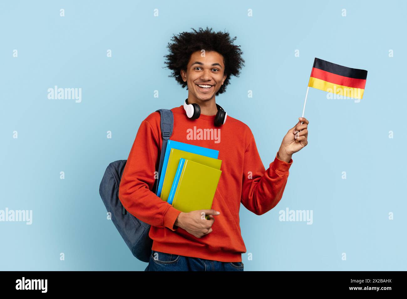 Friendly student holding German flag and books Stock Photo - Alamy