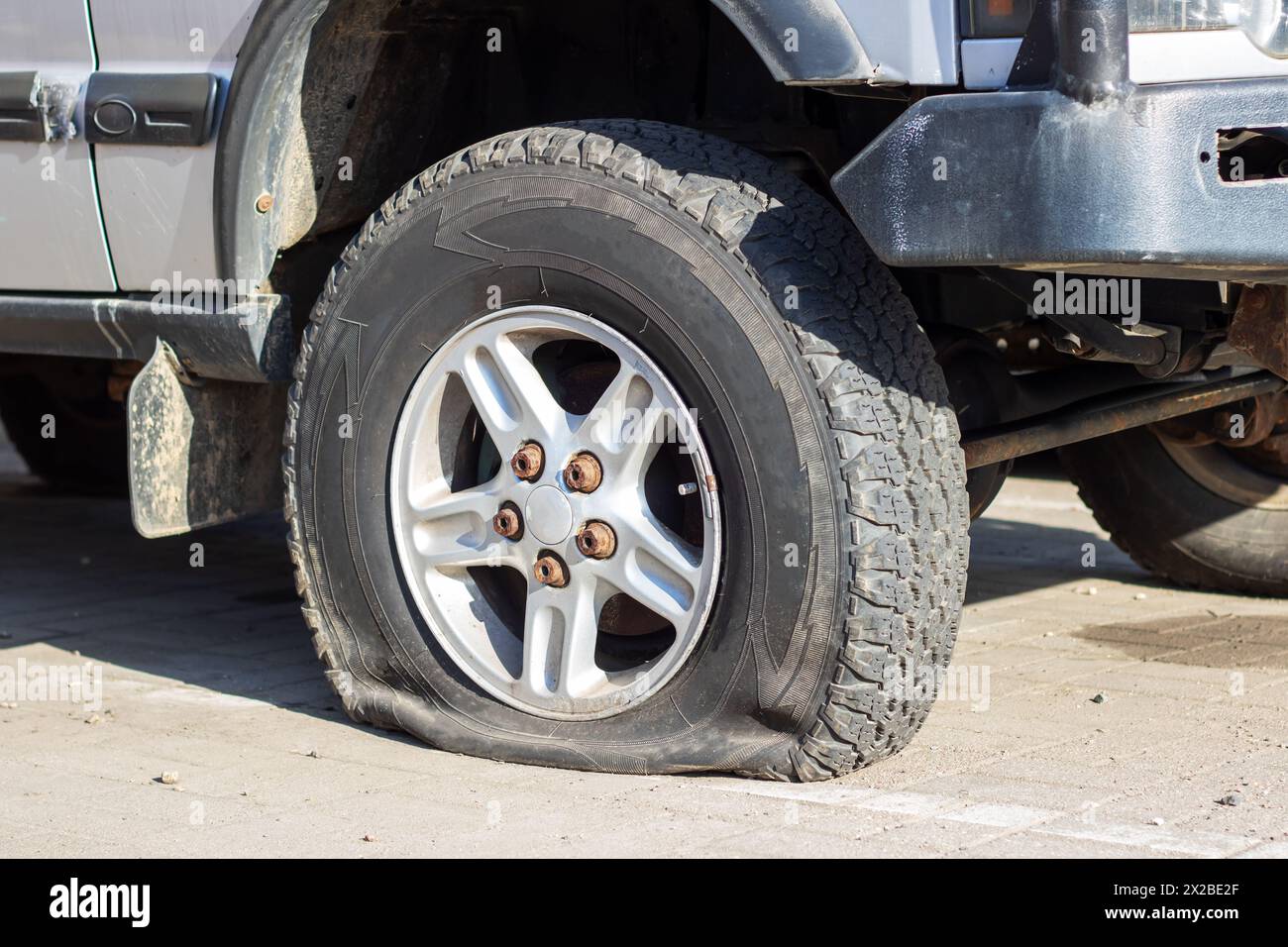 A car with a flat automotive tire on the side of the road, showing its ...