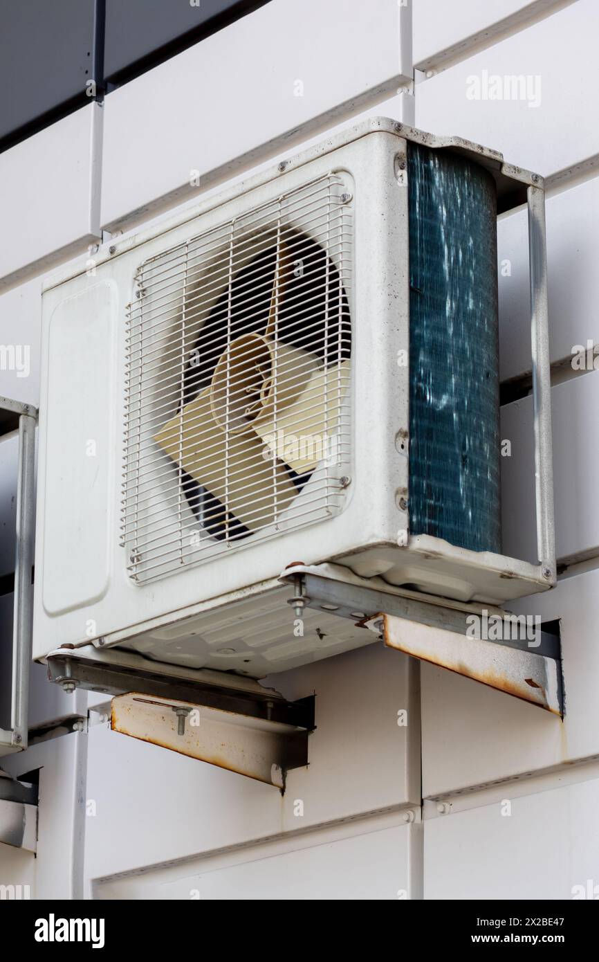 Two air conditioners are fixed on the brick facade of the building, one ...