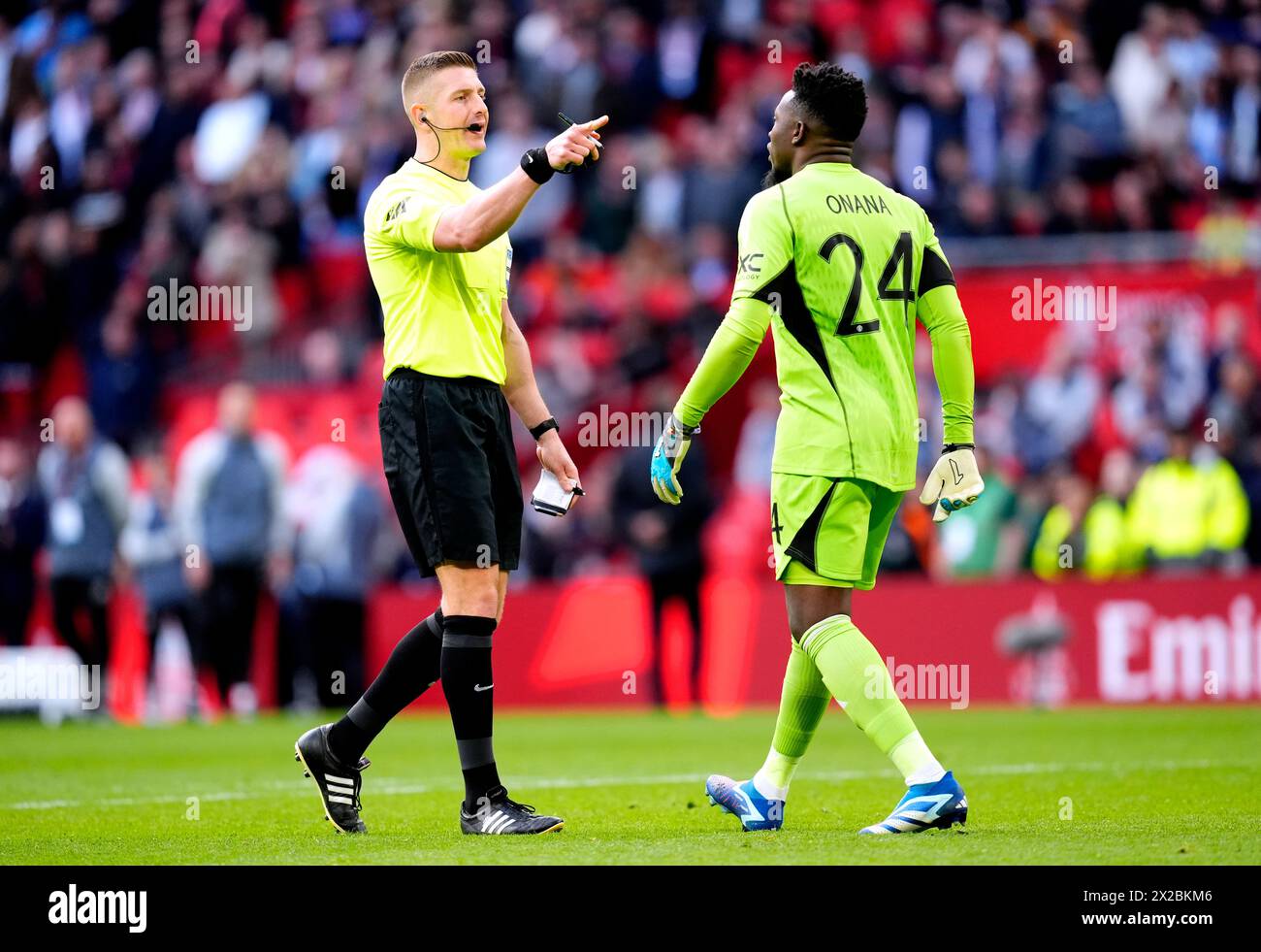 Referee Robert Jones speaks to Manchester United goalkeeper Andre Onana ...