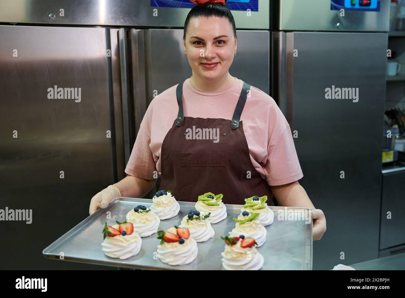 Smiling confectioner holding tray with crispy and tasty Pavlova ...