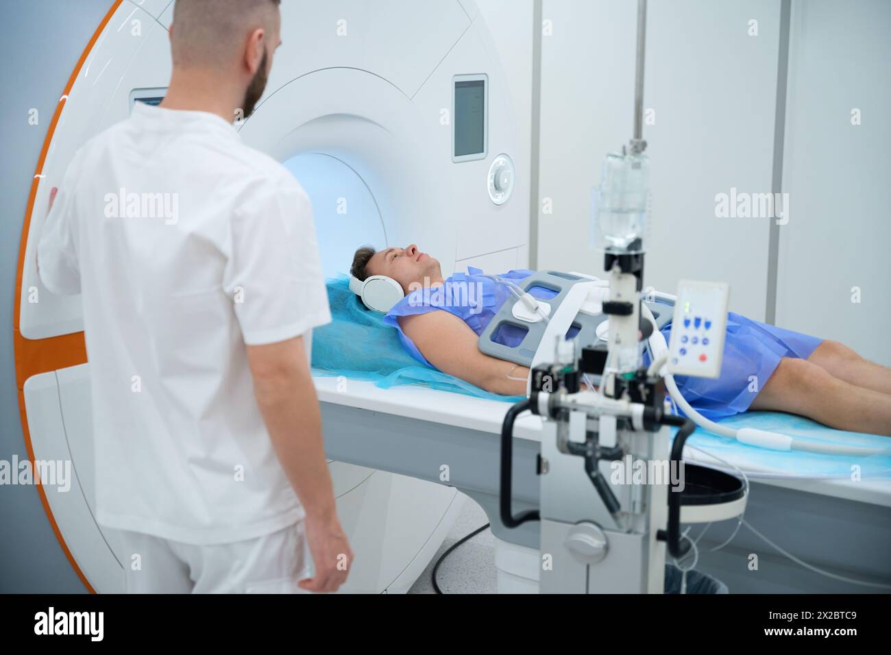 Doctor preparing male for contrast-enhanced abdominal magnetic ...
