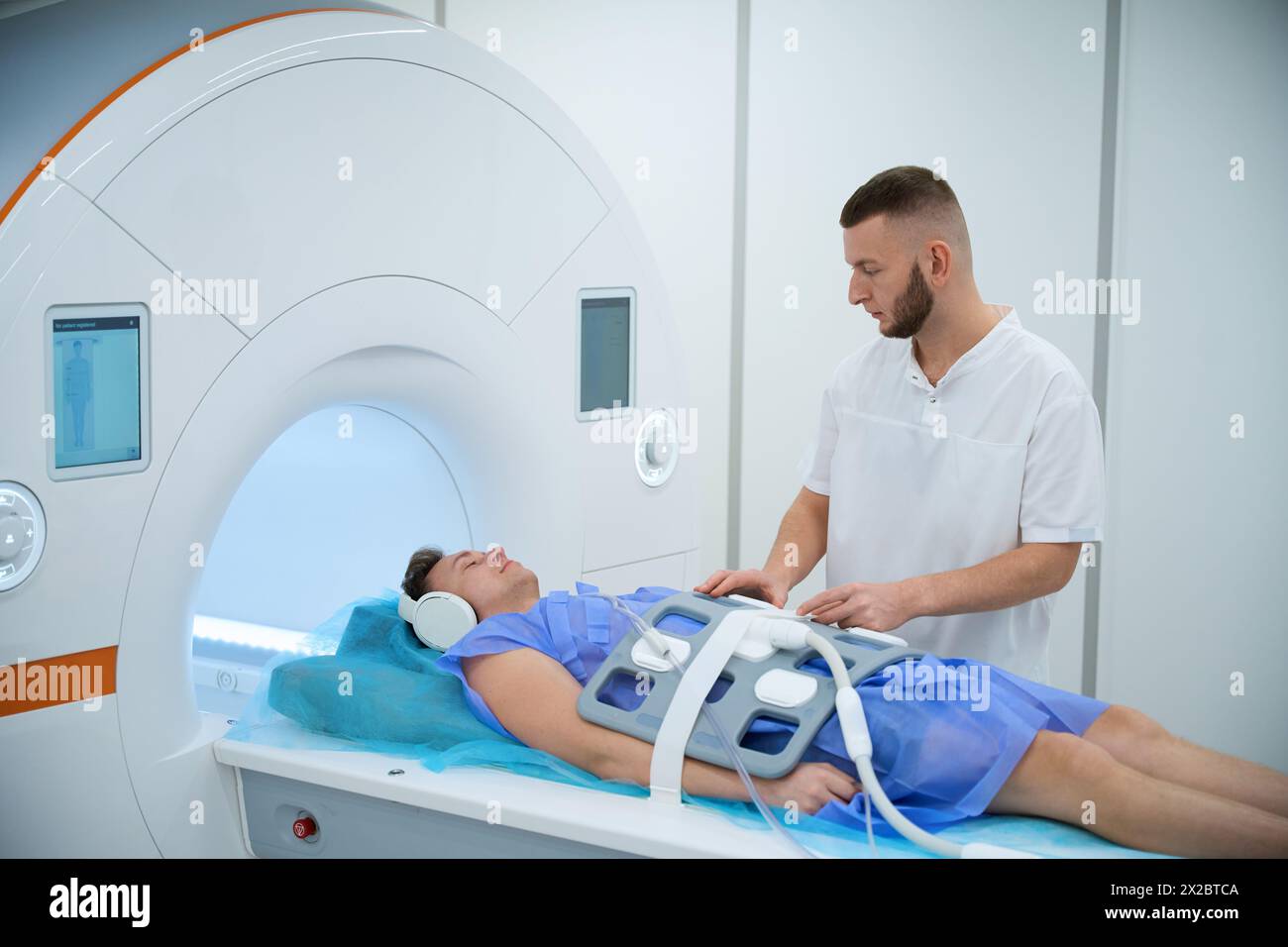 Technologist preparing man for abdominal magnetic resonance imaging ...