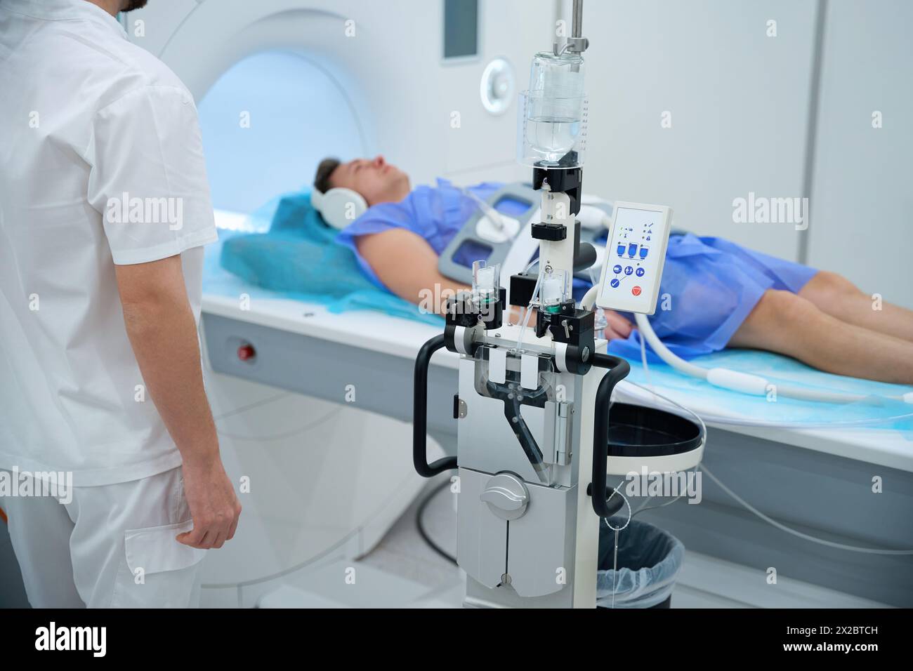 Doctor preparing man for contrast-enhanced abdominal magnetic resonance ...