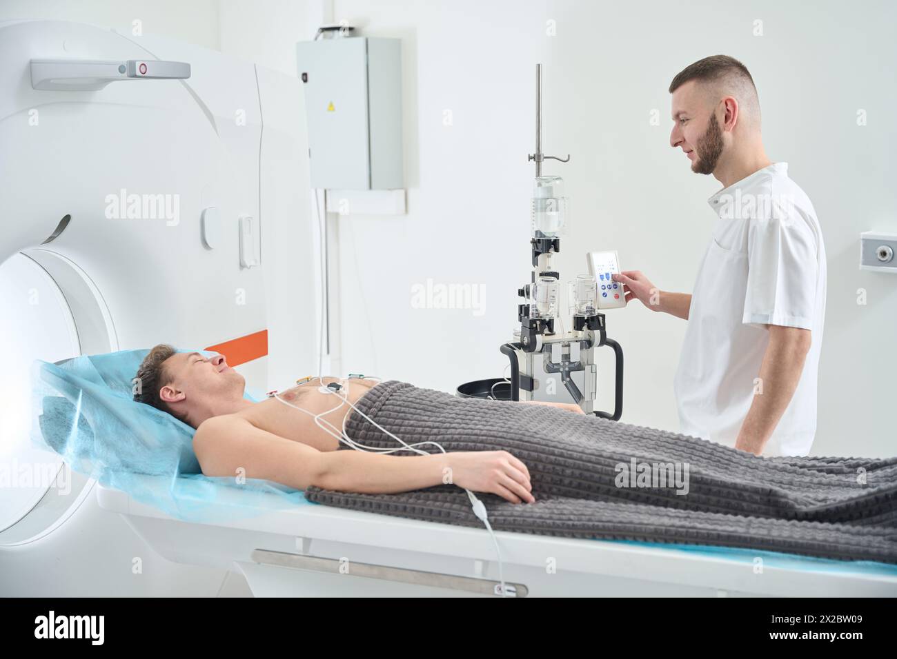 Doctor preparing man for contrast-enhanced ECG-gated coronary CT ...