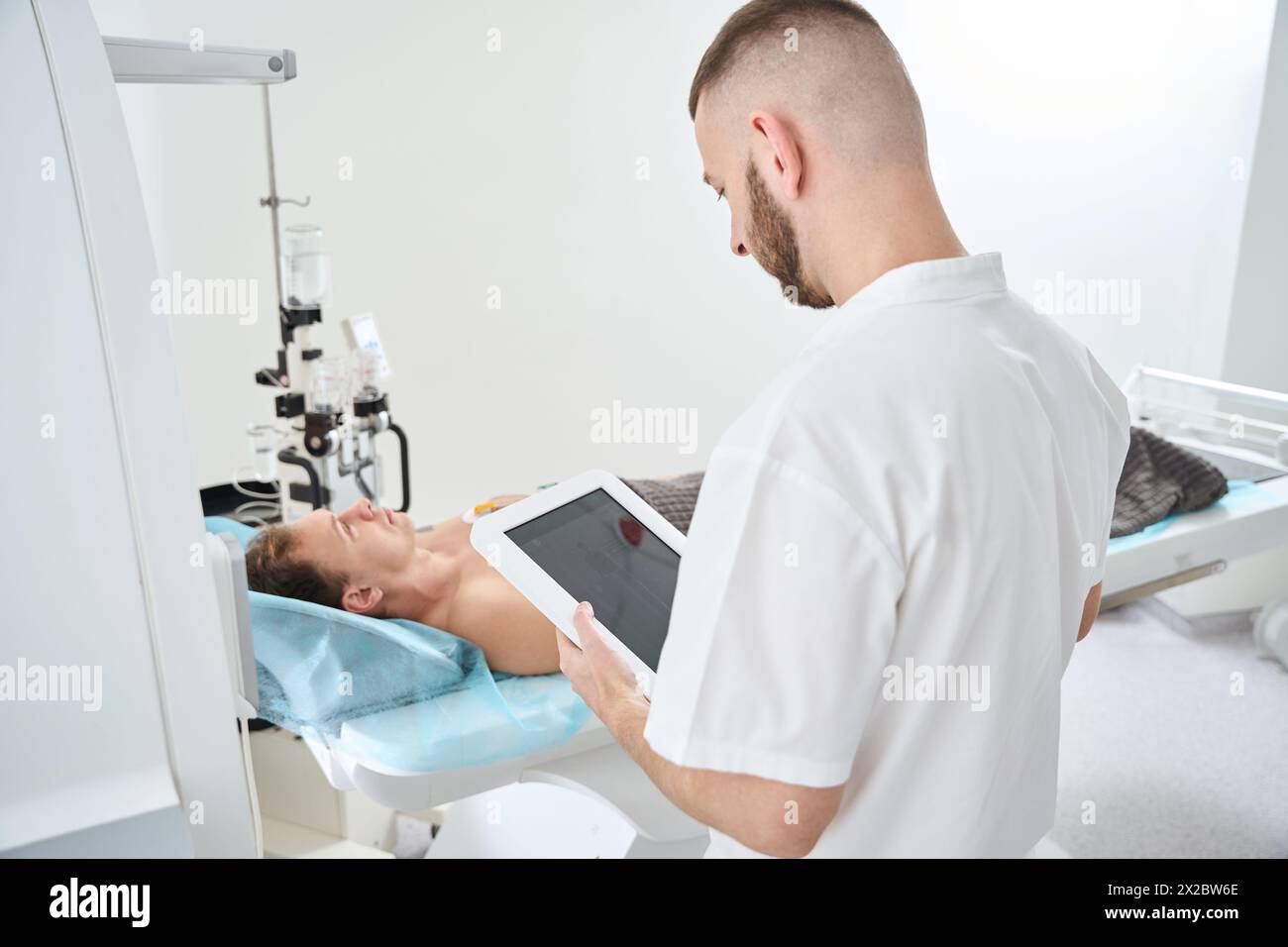 Doctor monitoring man before contrast-enhanced ECG-gated coronary CT ...