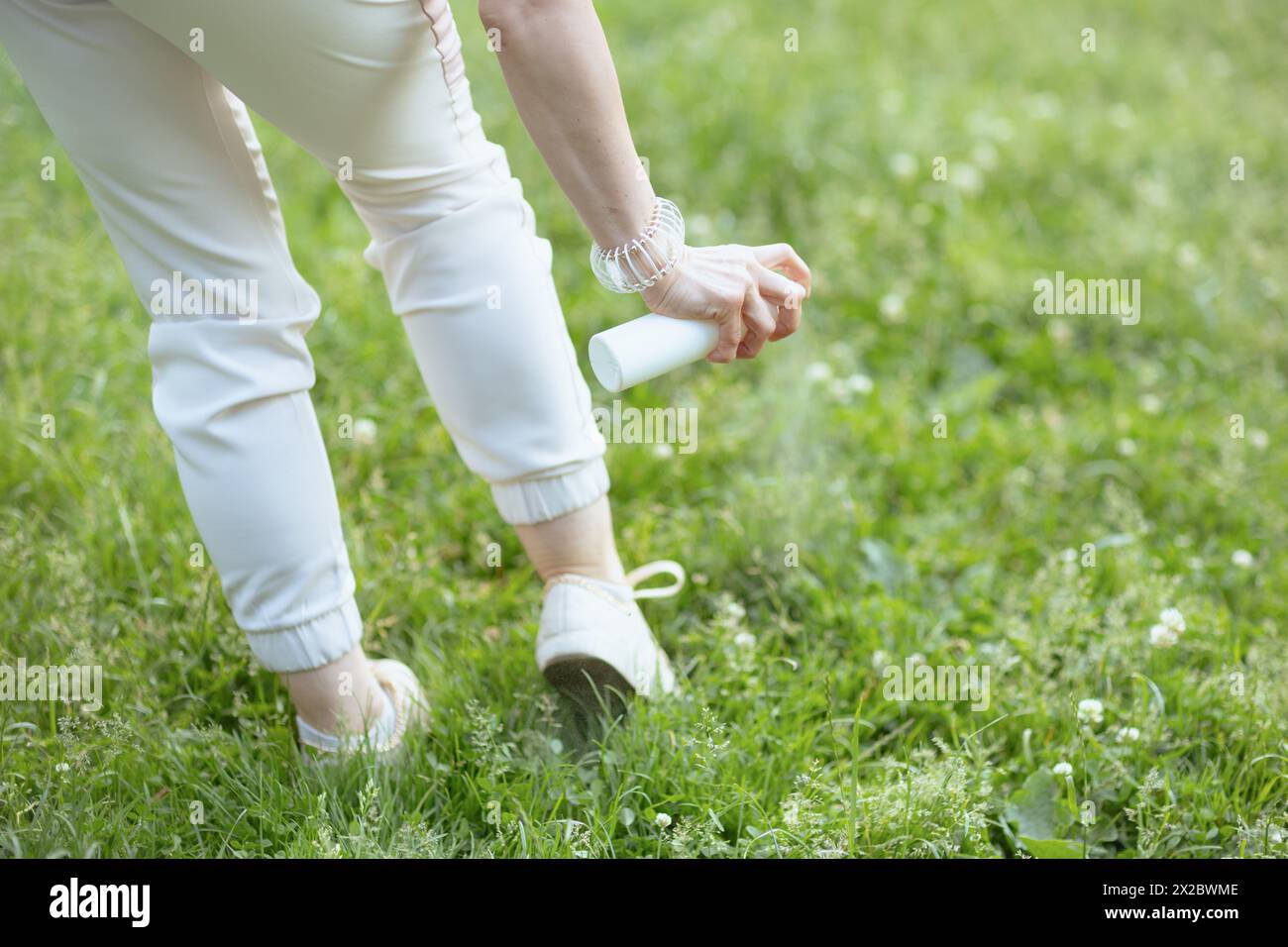 Summer time. Closeup on female using repellent spray in the meadow ...