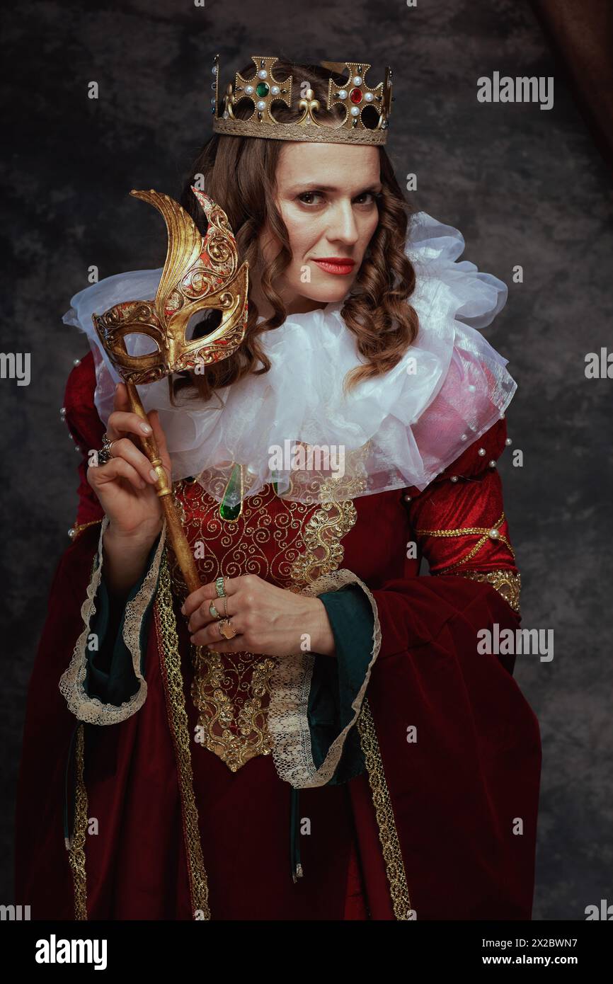 medieval queen in red dress with venetian mask, white collar and crown ...