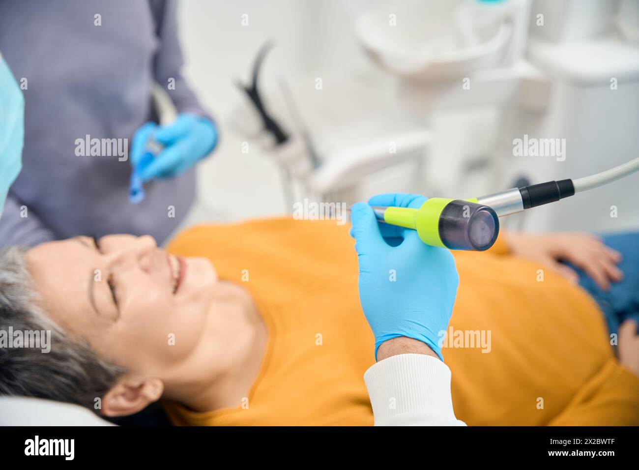 Dental hygienist going to polish female client teeth using special ...