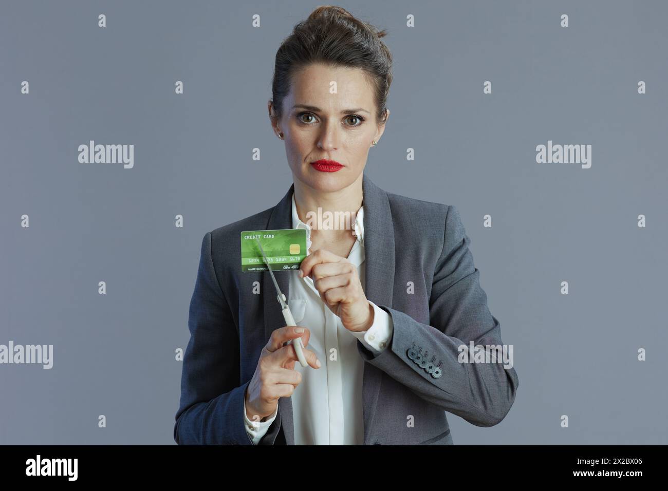 sad trendy 40 years old woman employee in gray suit with credit card ...