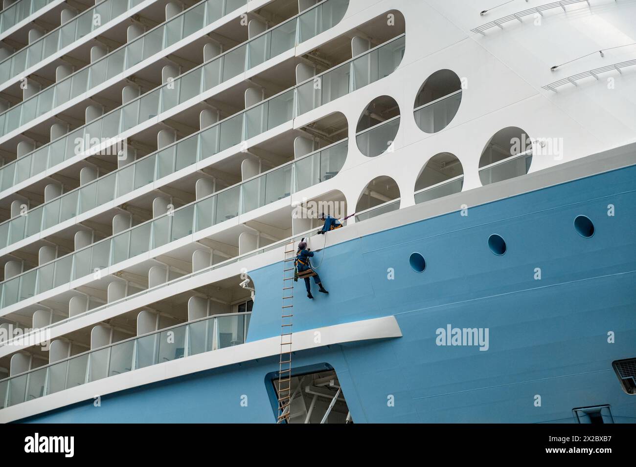 A dedicated worker meticulously cleans a majestic blue cruise ship ...