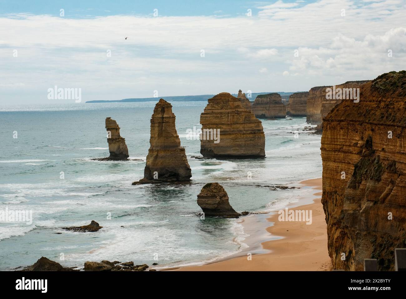 A picturesque view of the Twelve Apostles along the beach, set against ...
