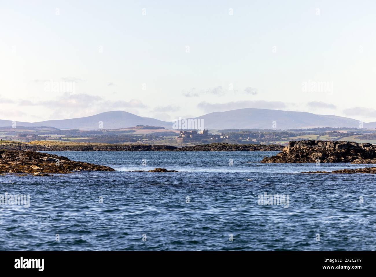 Bamburgh Castle seen at a distance from the Farne Islands. In the far ...