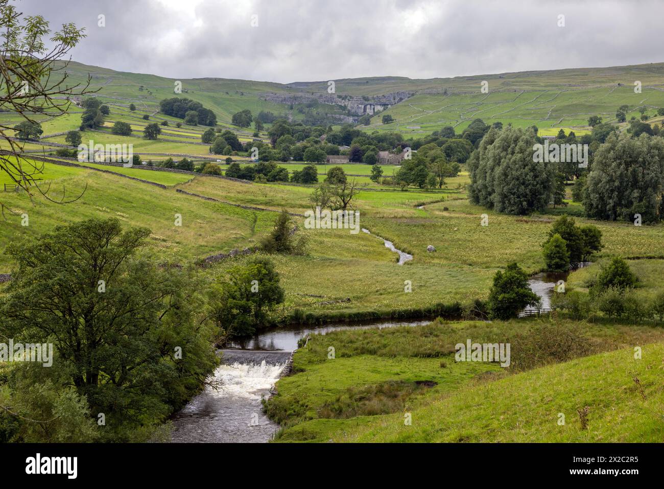 The Pennine Way. The River Aire, with Malham Cove in the distance Stock ...