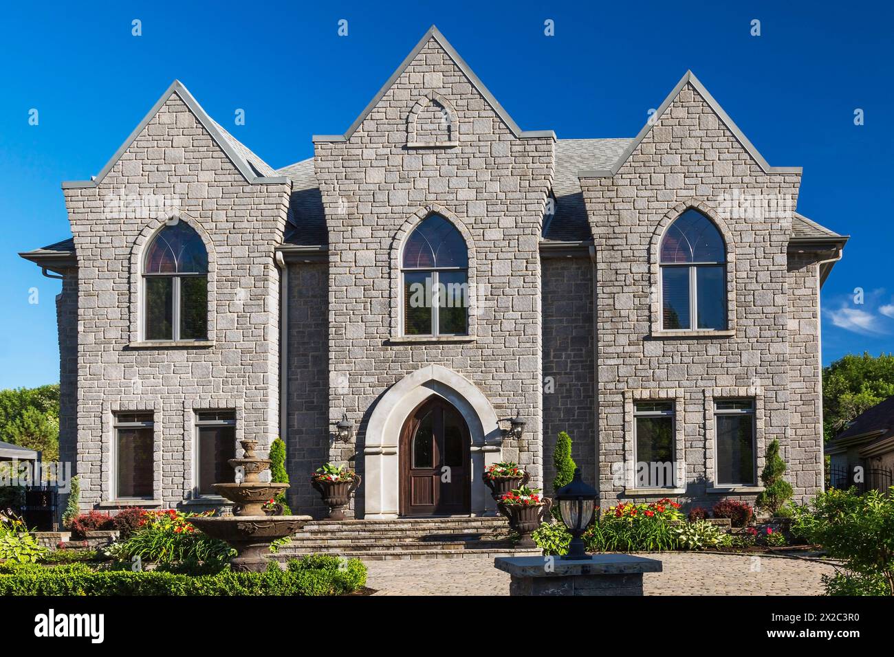 Two story grey nuanced cut stone Gothic style home facade with ...
